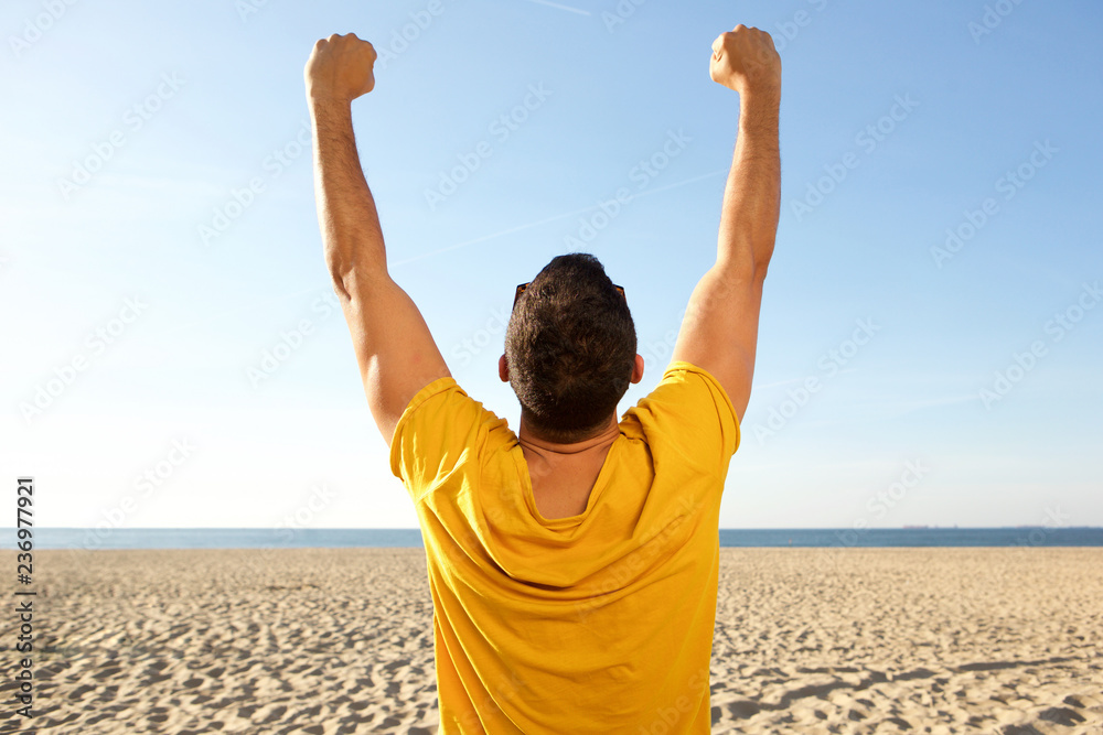 back of man cheering with arms raised at the beach Stock Photo | Adobe ...