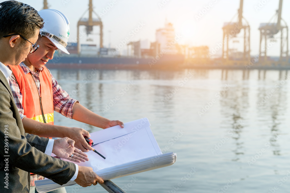 Civil engineer checking drawing with walkie-talkie with management team ...