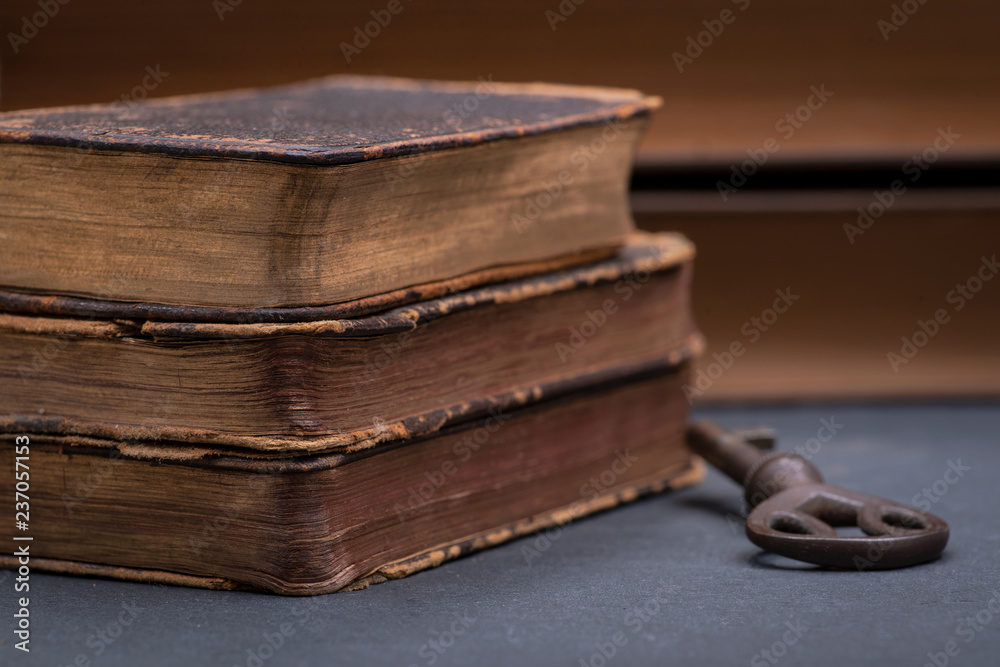 Pile of old vintage hard cover books and antique metallic key on ...