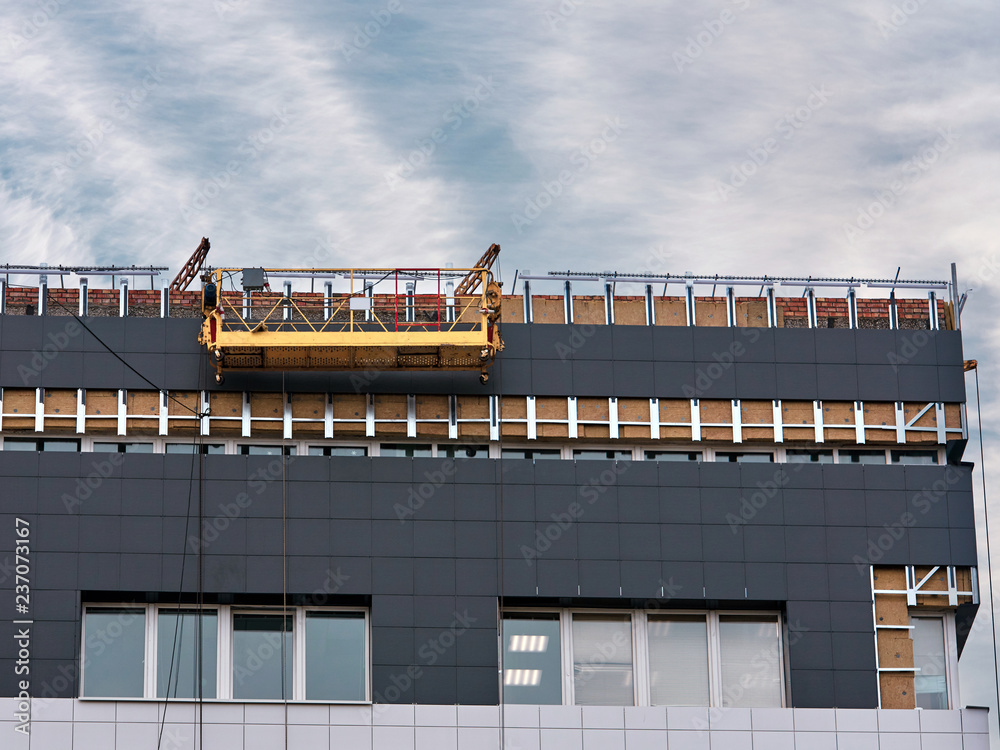 Cradle of construction crane. insulate, repair facade of house. Energy ...