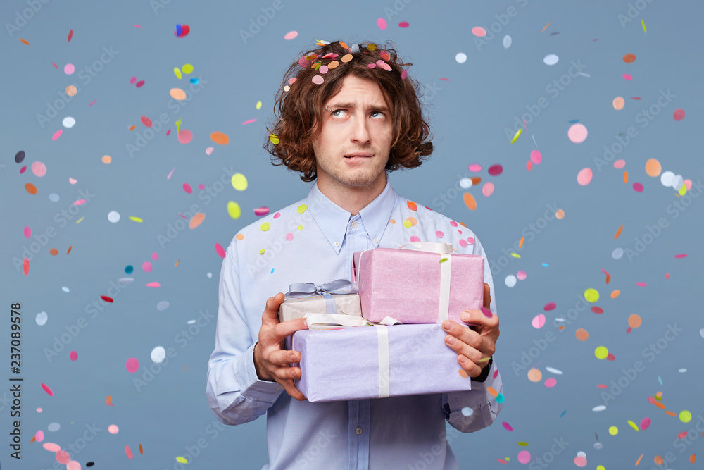 Young man accepts gifts for a birthday, holds boxes tied up with ...
