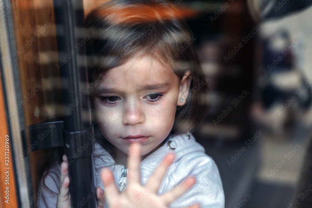 Little crying girl standing overLittle crying girl standing behind the ...