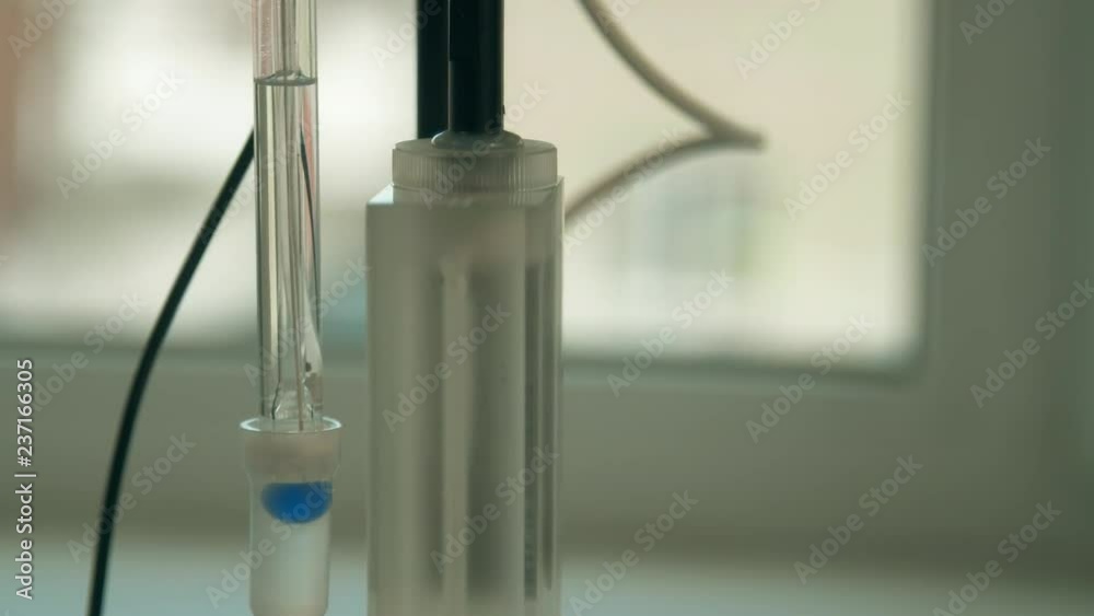 Electrode from pH meter is lowered into the liquid and measures level ...