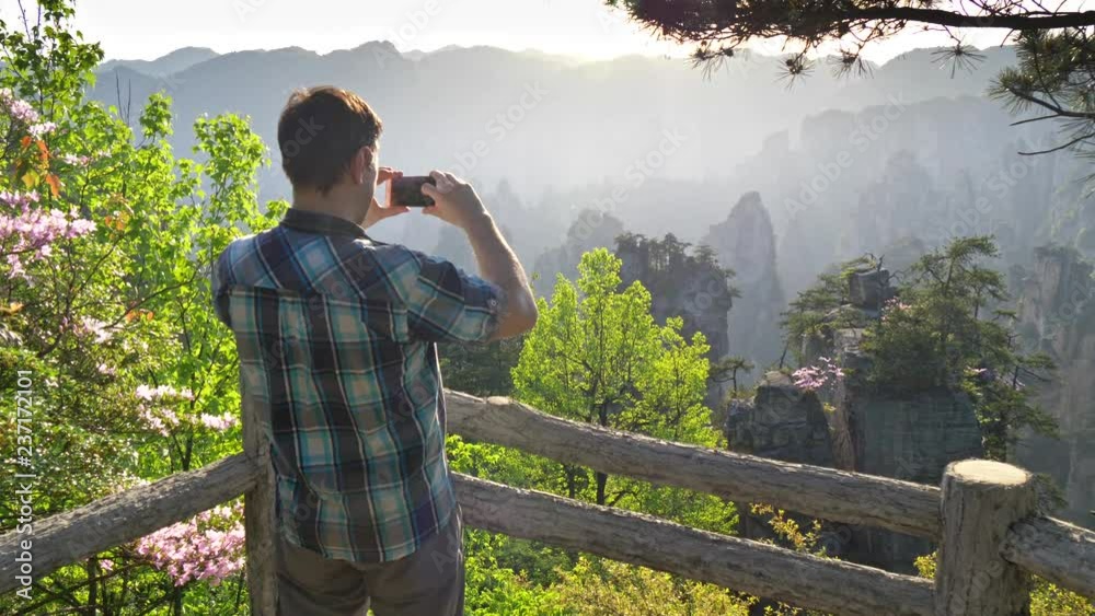 A tourist making snapshots of scenic views of vertical cliffs in ...
