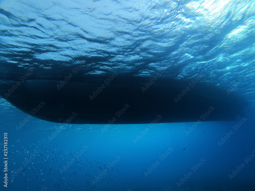 Big ship from down underwater top view with shining light sky and wavy ...