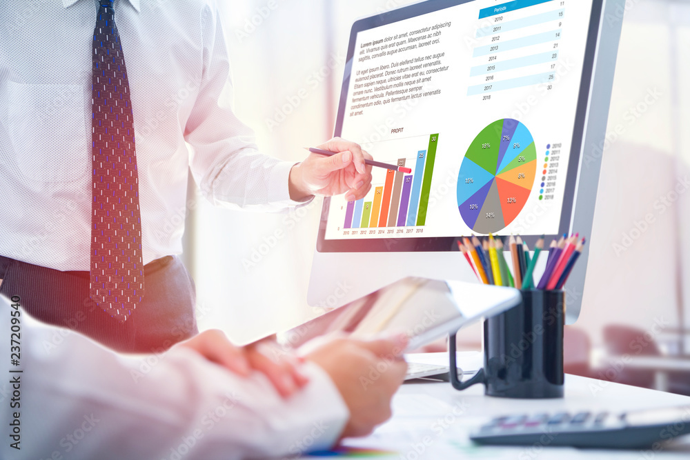 Two businessmen looking into a modern computer screen reviewing a ...