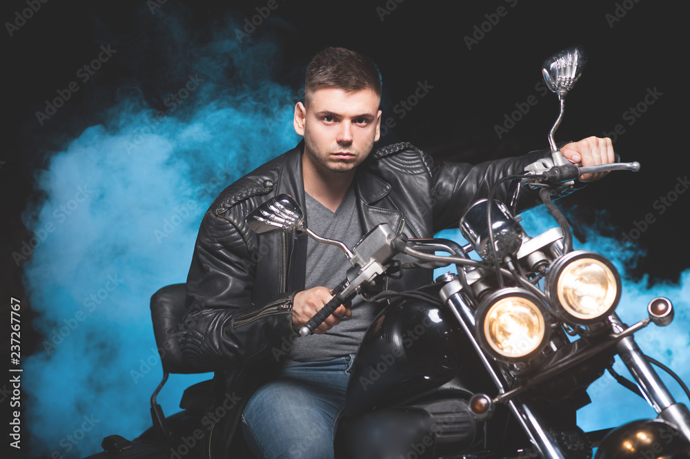 Cute biker in leather jacket sits on a motorcycle in blue smoke Stock ...
