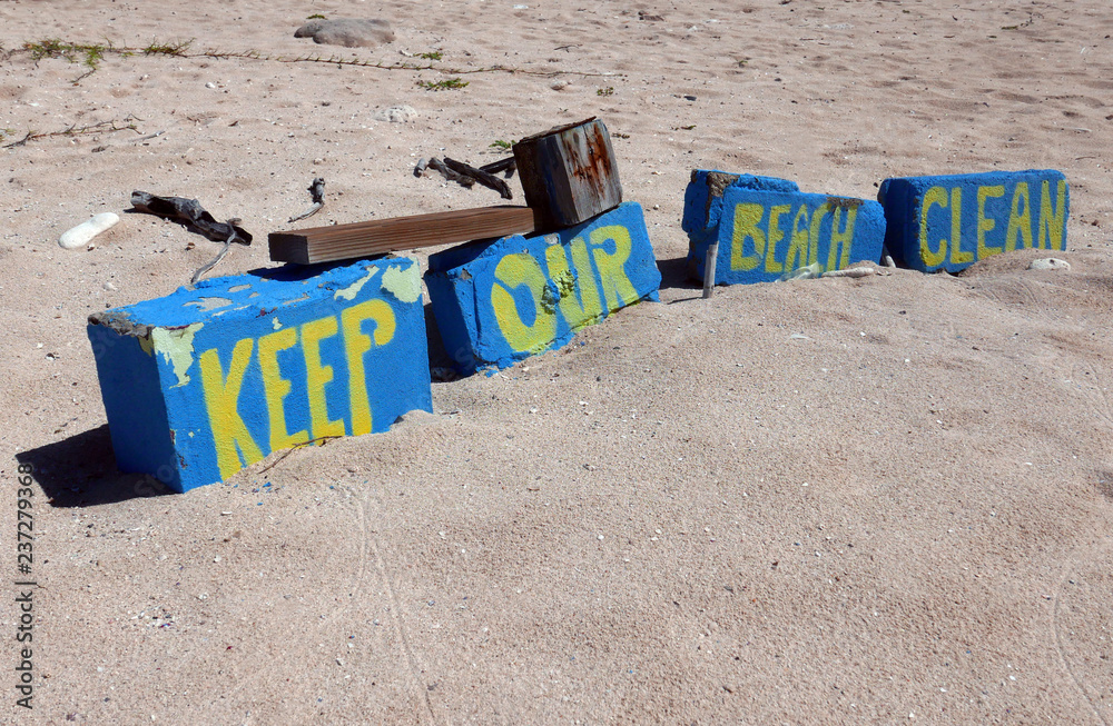 Sign Keep our Beach clean in yellow letters stenciled on blue bricks ...