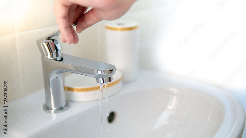 Male hand opening water tap or faucet in bathroom. Save water at home ...