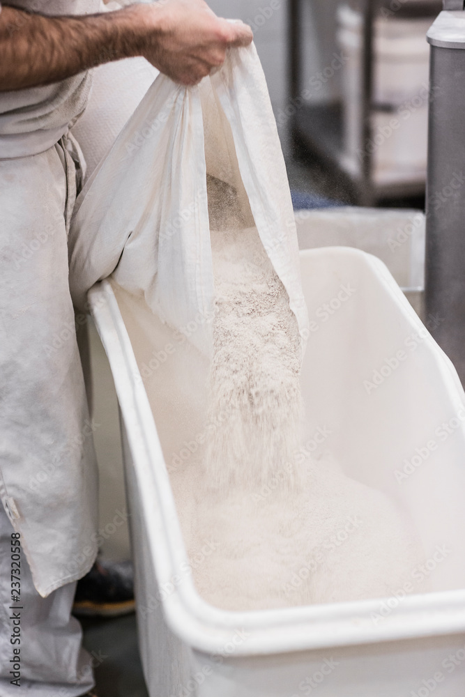 Man baker pouring flour from commercial bag Stock Photo | Adobe Stock