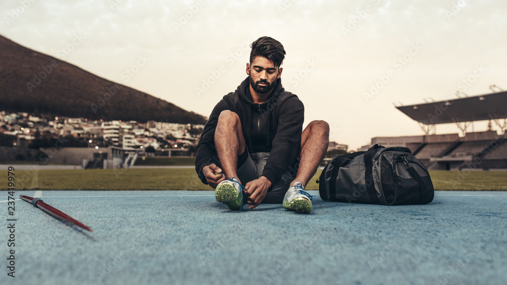 Athlete sitting on running track wearing his shoes Stock Photo | Adobe ...
