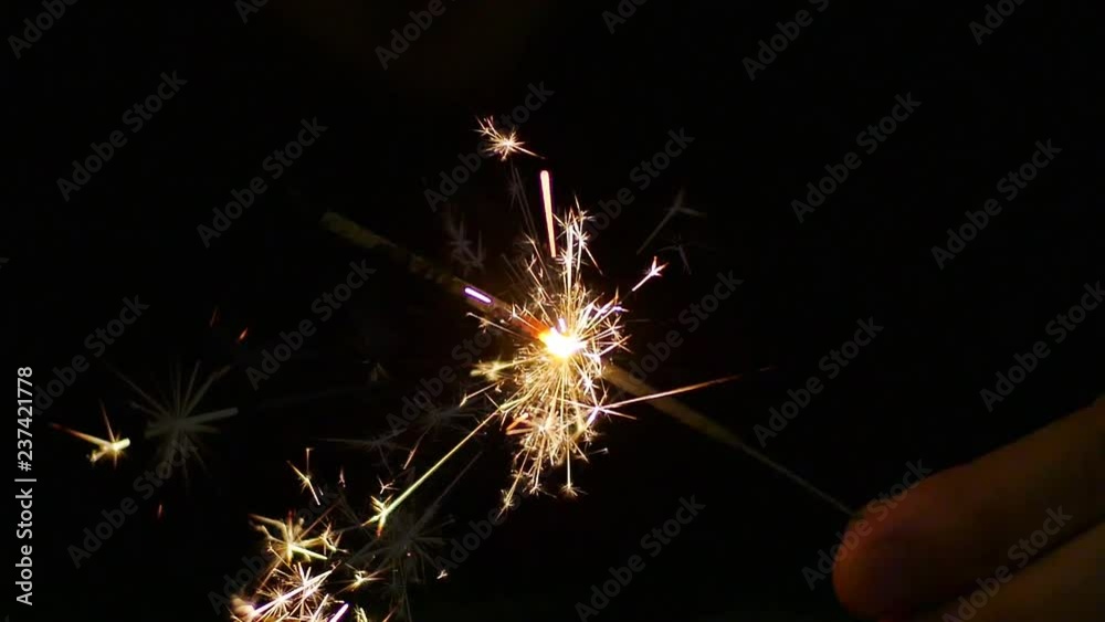 Slow Motion. Hand holds burning sparkler over dark background. Bengal ...