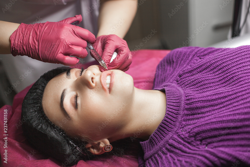 Procedure of lip augmentation in the beauty salon. Cosmetologist making ...