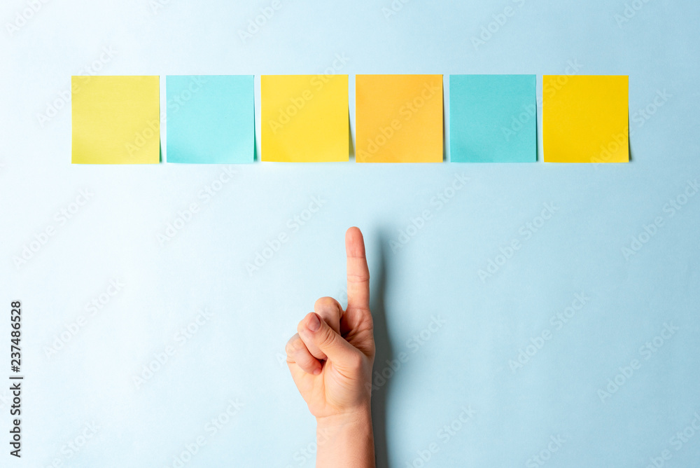 Hand with the index finger pointing up the multicolored notes on blue ...