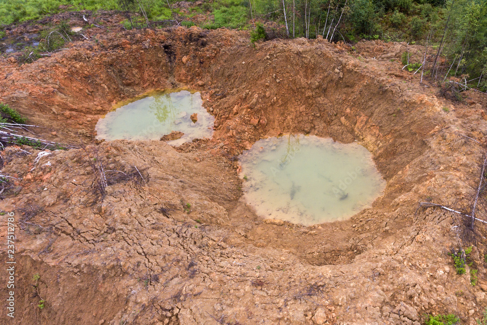 Holes on ground from powerful explosions. Bomb craters in the forest ...