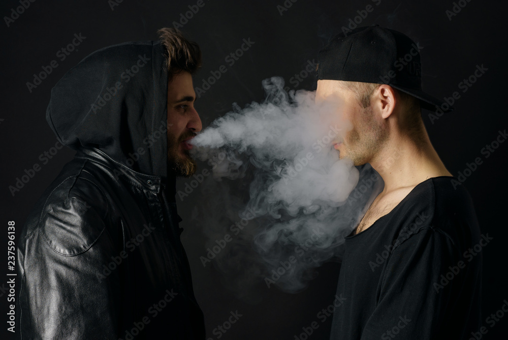 Bad habit, smoking in a public place. Two Young man blowing smoke to ...