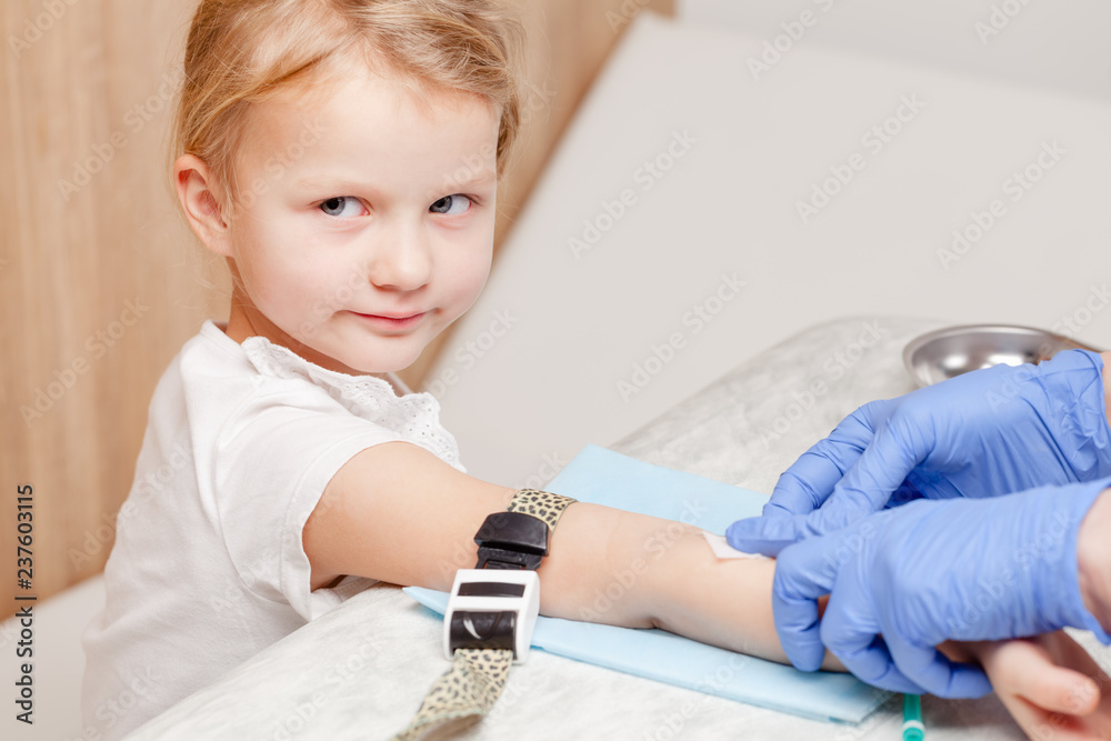 Nurse takes a blood sample from little girls arm - pediatric ...