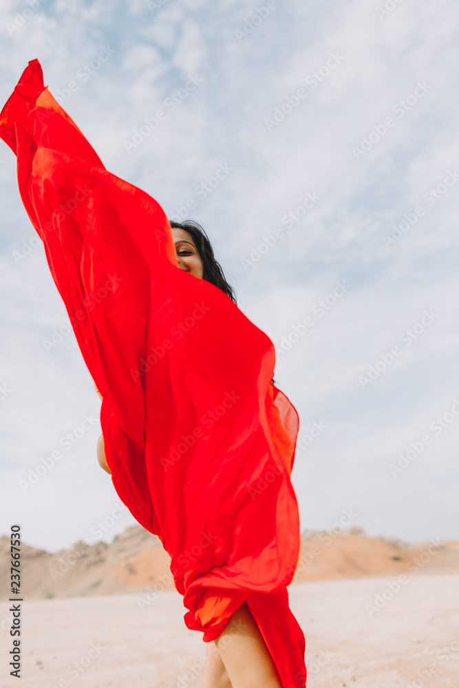 Young beautiful indian woman walking in red dress in the desert with ...
