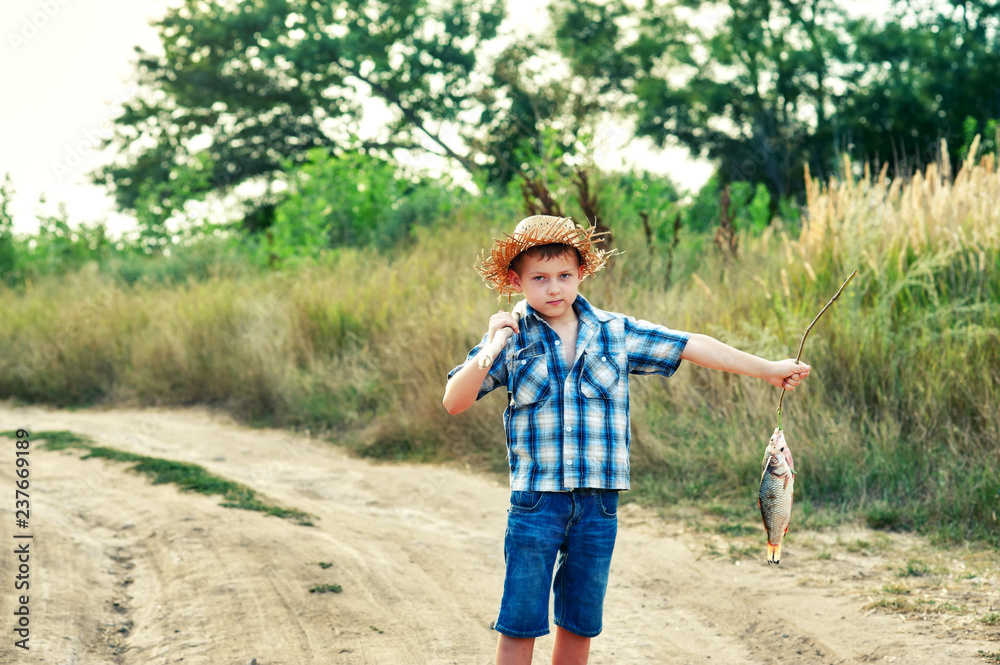 Portrait of a cheerful boy going fishing . the boy is holding a river ...