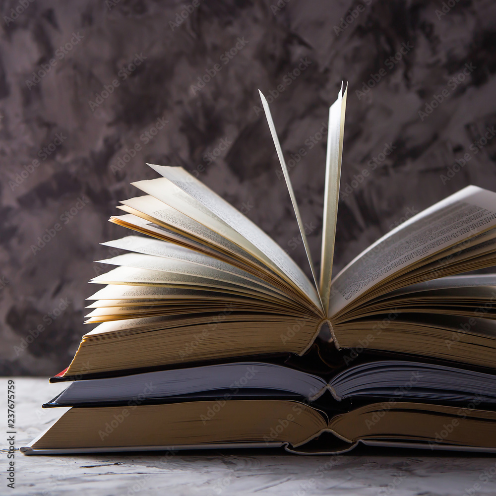 A stack of open books with flipped pages on a gray background. Learning ...