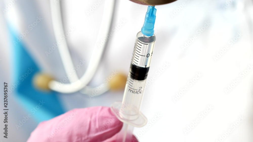 Medical doctor picking up medication into a single use syringe and ...