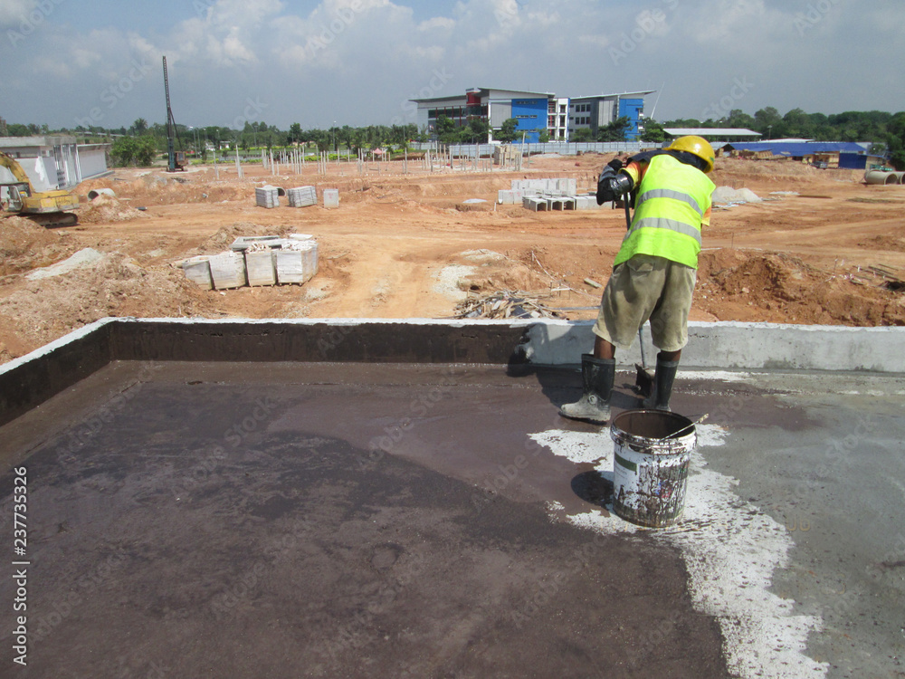 Construction worker apply layer of bituminous waterproofing at the ...