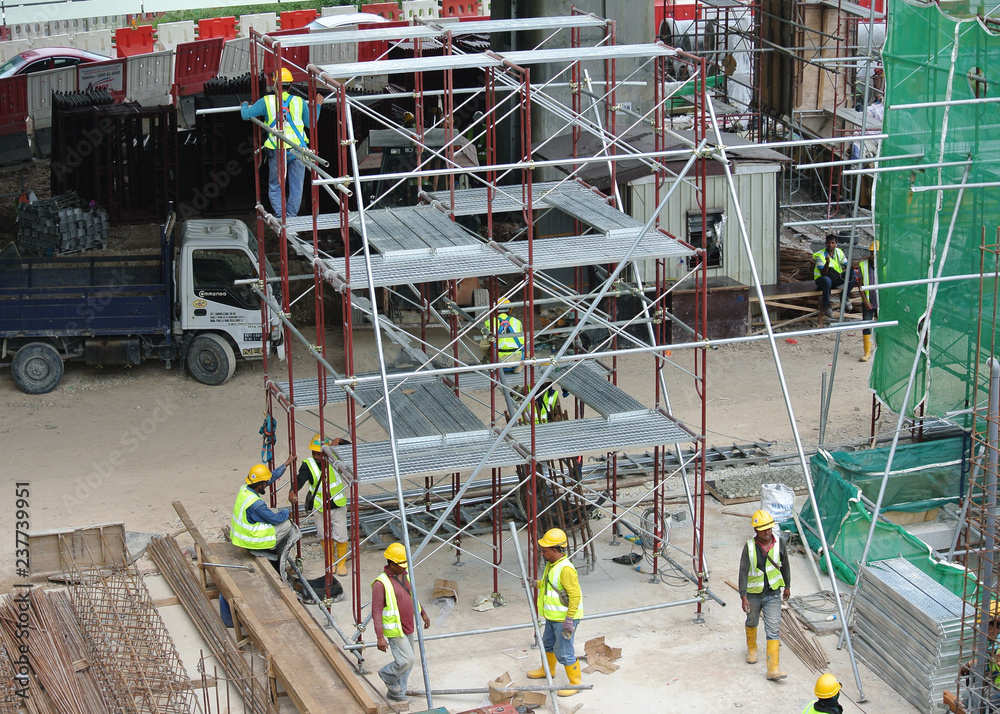 Construction workers wearing safety harness and adequate safety gear ...