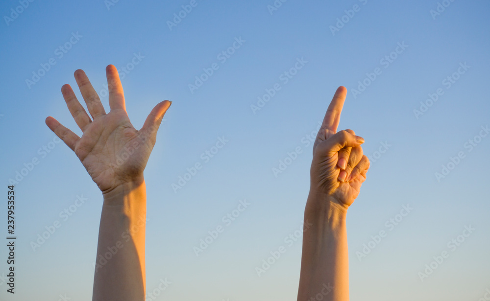 Hands doing / showing number six gesture symbol on blue summer sky ...