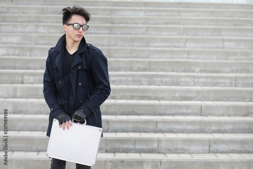 Asian man with a metal suitcase in the city. Asian and silver case ...