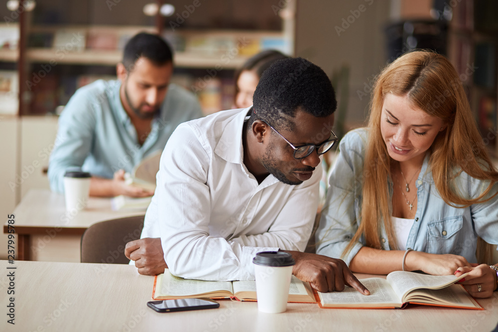 Group of concentrated multiracial diverse students reading books ...