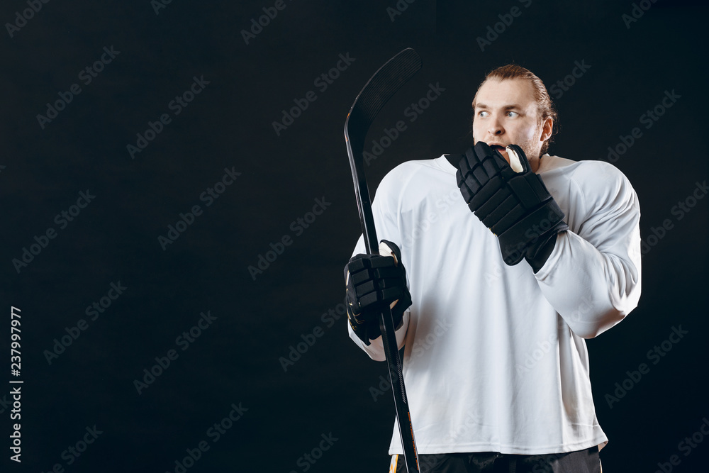 Handsome hockey player man holding hockey stick covers mouth with hand ...