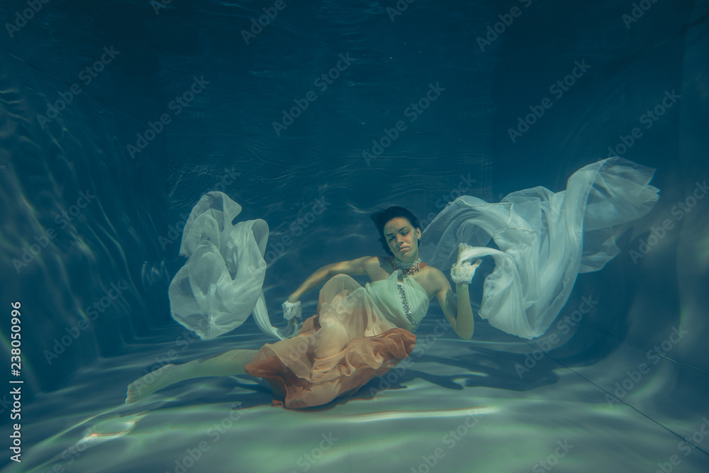 elegant slender girl swims underwater like a free diver in a white ...