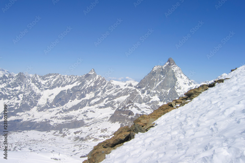 snowless pyramidal peaks and sheer cliffs of mountain range sloping ...