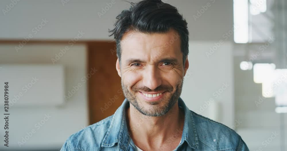Portrait of a smiling handsome middle aged man in living room in slow ...