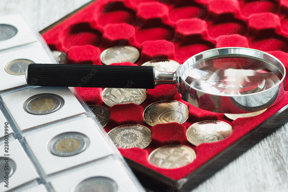 Different collector's coins in the box and a magnifying glass foto de ...