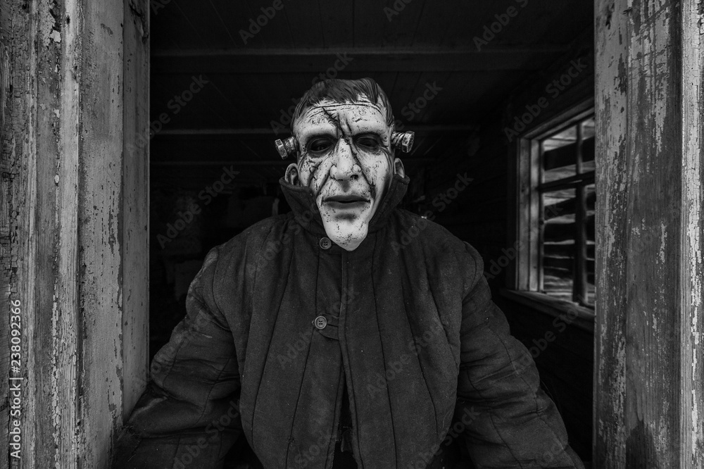 Unknown person with creepy horrible latex mask looking out from old ...