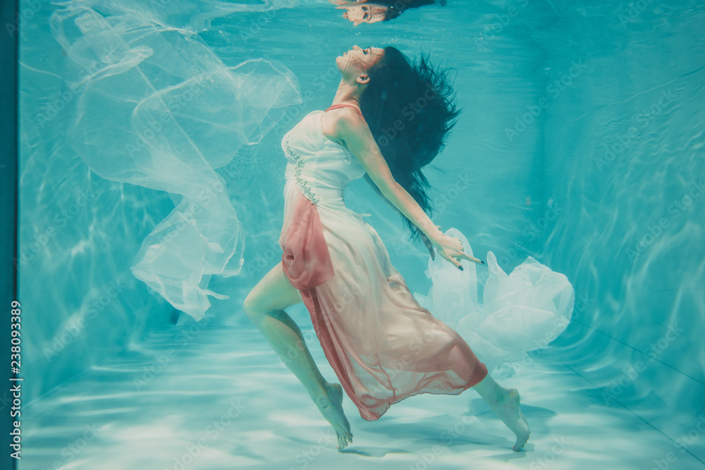 beautiful model girl swimming underwater in feminine long white and ...