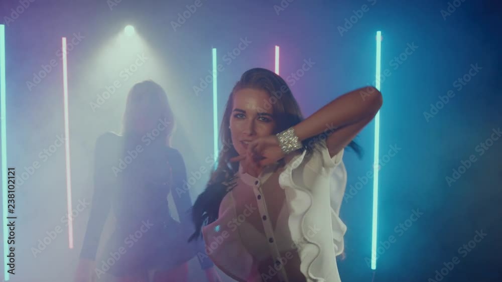 Sexual dancer girls are moving rhythmically by music in dark nightclub ...