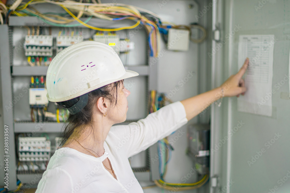 female electrician checks the electrical box. A girl in an engineering ...