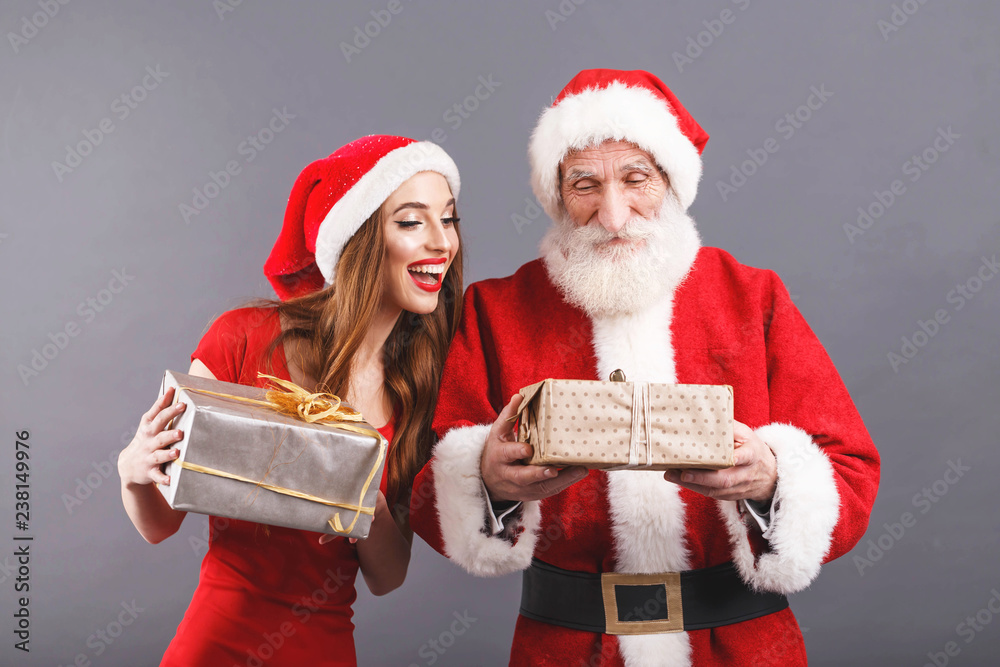 Santa Claus with white beard wearing sungasses and young mrs. Claus ...