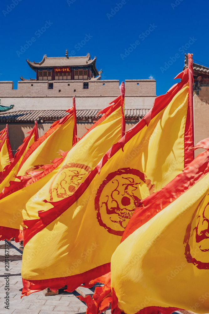 Red and yellow flags in front of traditional Chinese buildings at Jiayu ...