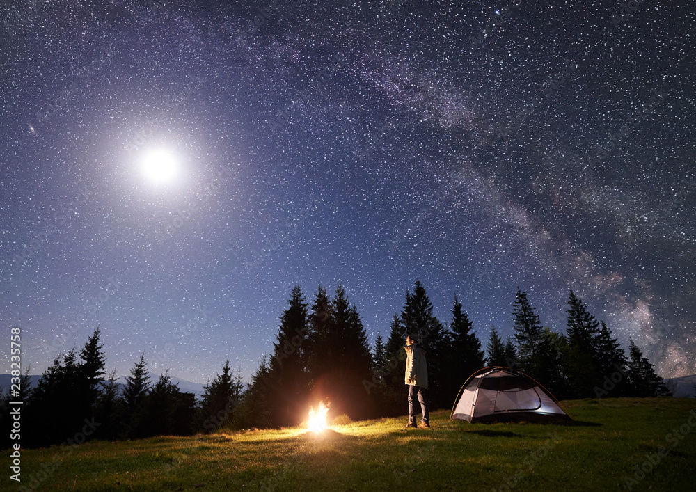 Camping site in mountain valley at night. Male backpacker having a rest ...