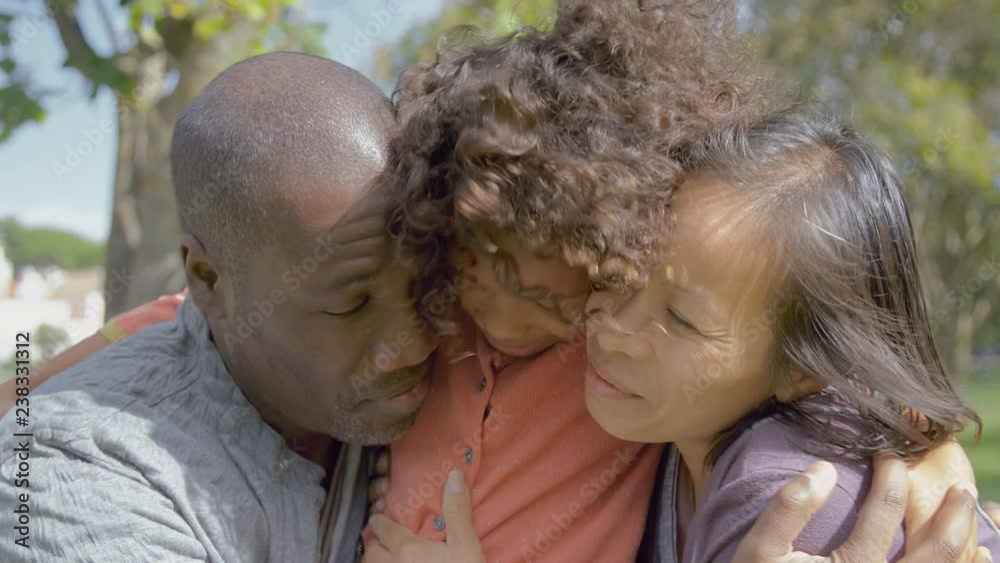 African American curly daughter embracing happy parents in park ...