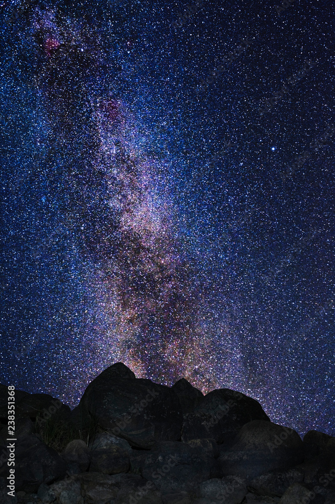 Milky Way and stars in the night sky. Big rocks in the foreground ...
