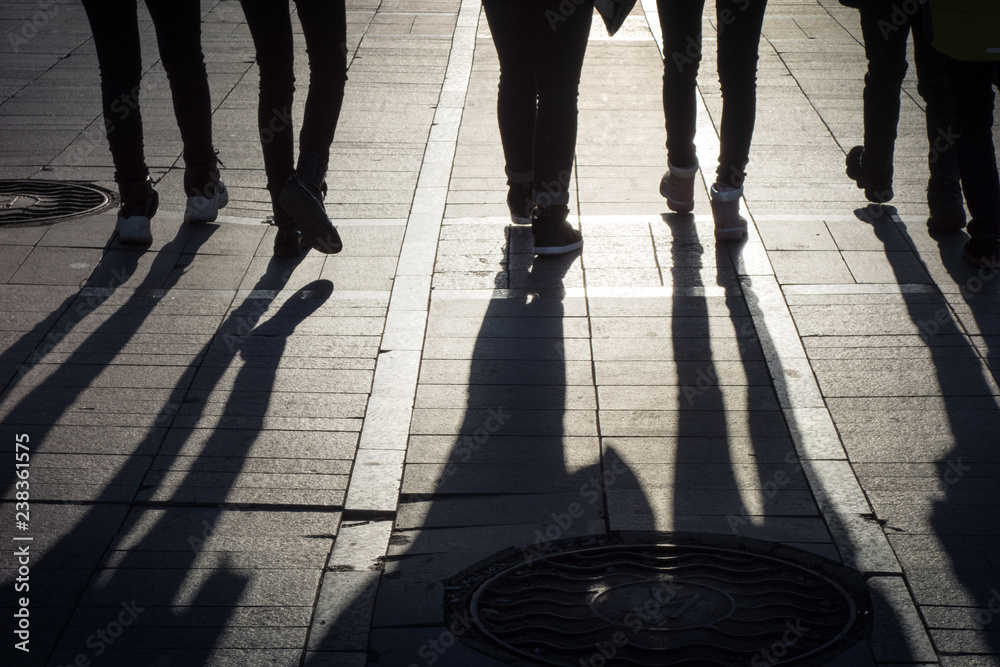 Silhouettes and shadows of people walking along a city street. Contrast ...
