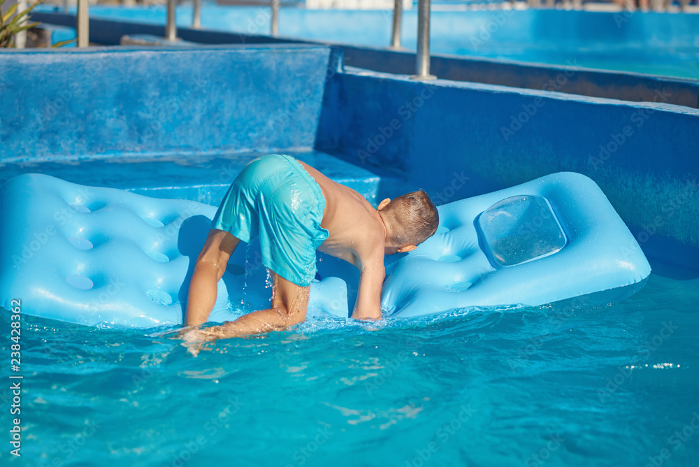 Caucasian boy getting out from water on inflatable mattress in swimming ...