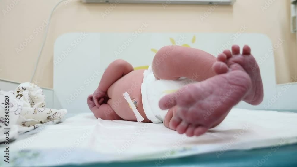 Newborn baby girl lying on back. Baby is kicking and stretching legs ...