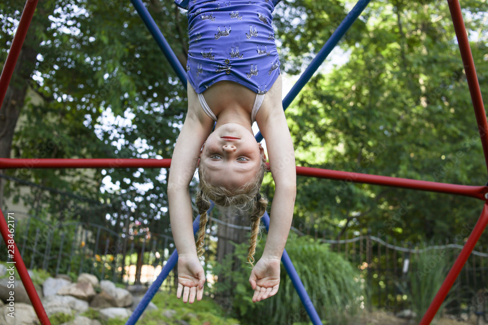 Girl hanging upside down on jungle gym in playground Stock 写真 | Adobe Stock