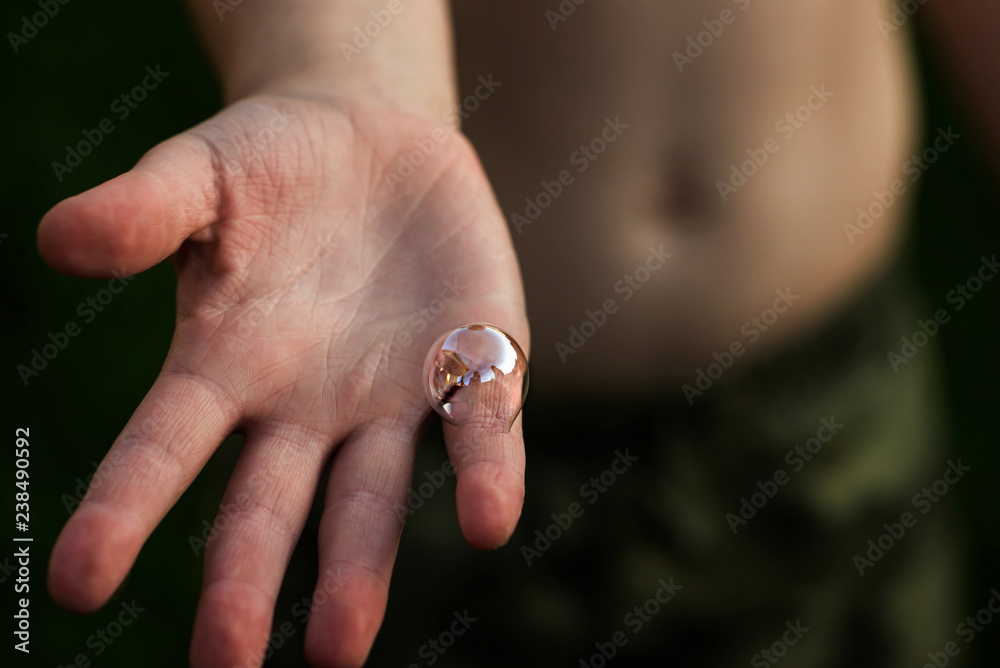 Midsection of shirtless boy showing bubble on hand while standing ...