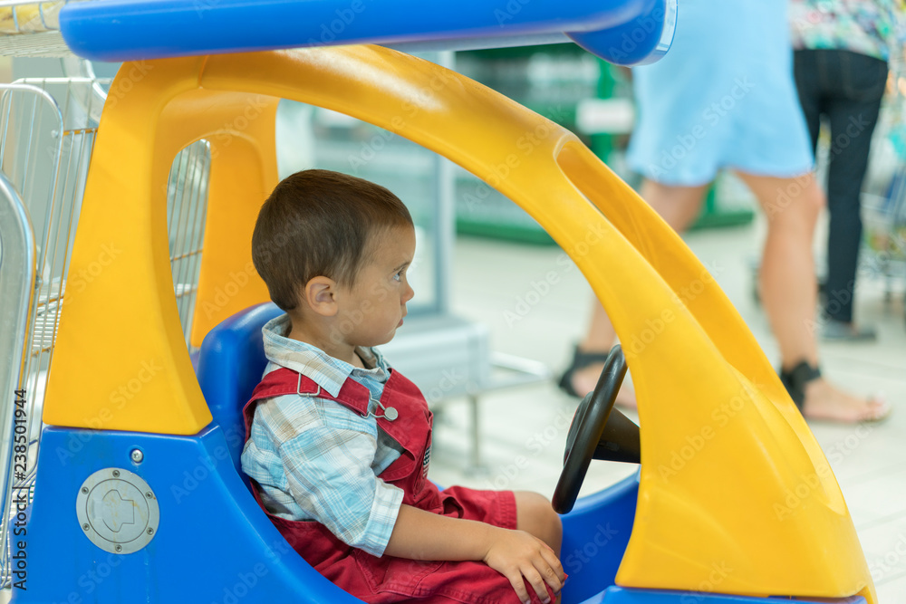 Cute little 2 year old baby boy child in the little toy-car trolley at ...